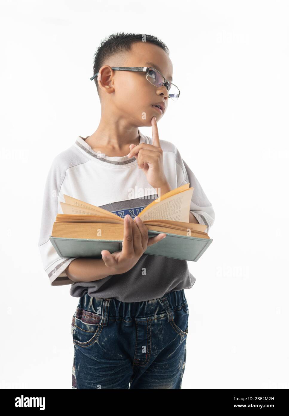 portrait of cute Asian boy student thinking and holding big book ...
