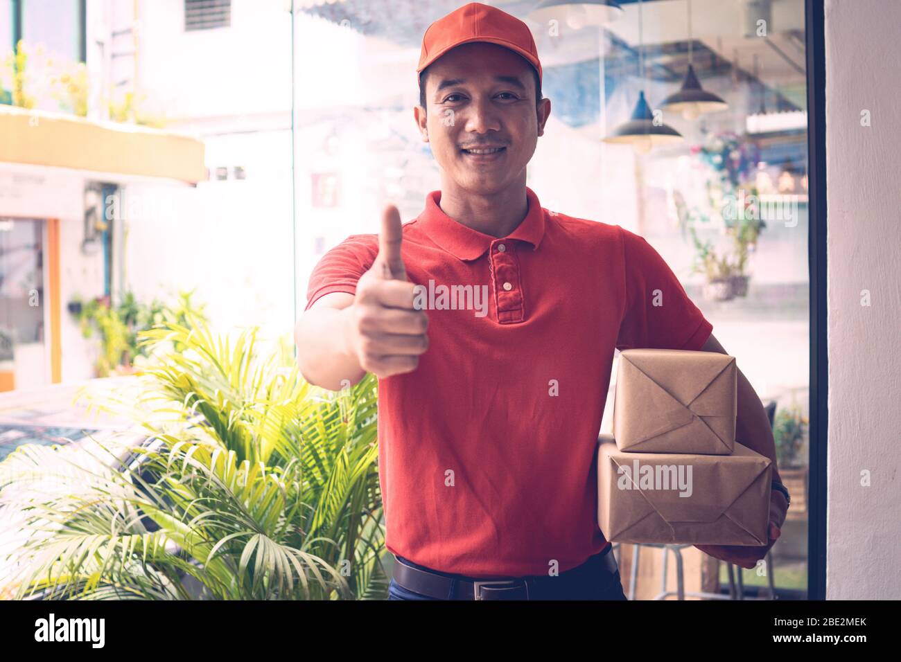 Postman holding parcel and showing thumb up to certificate and confirm ...