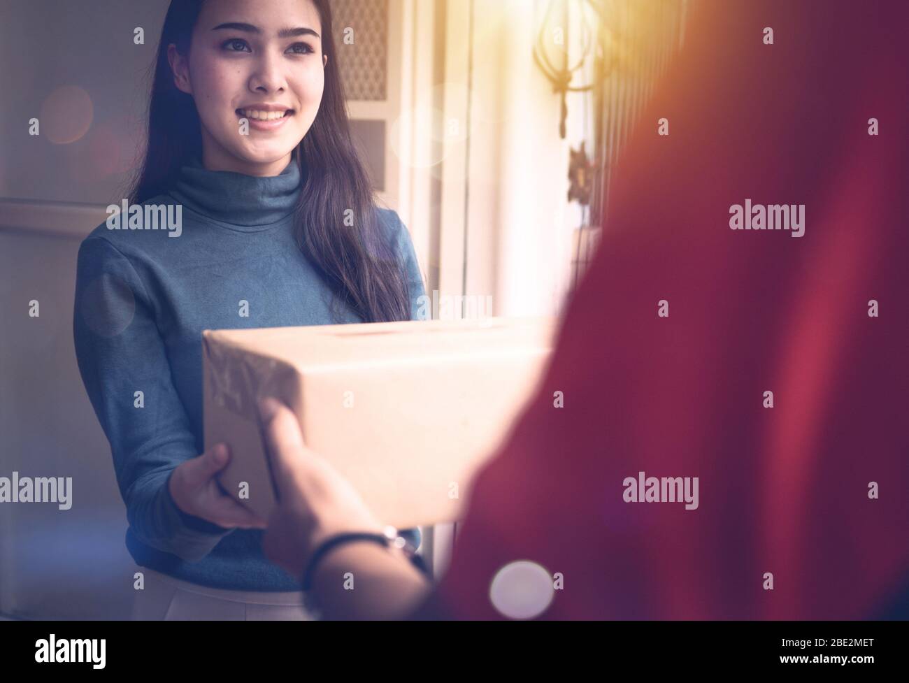 Beautiful girl smiling and receiving parcel from postman that delivery ...