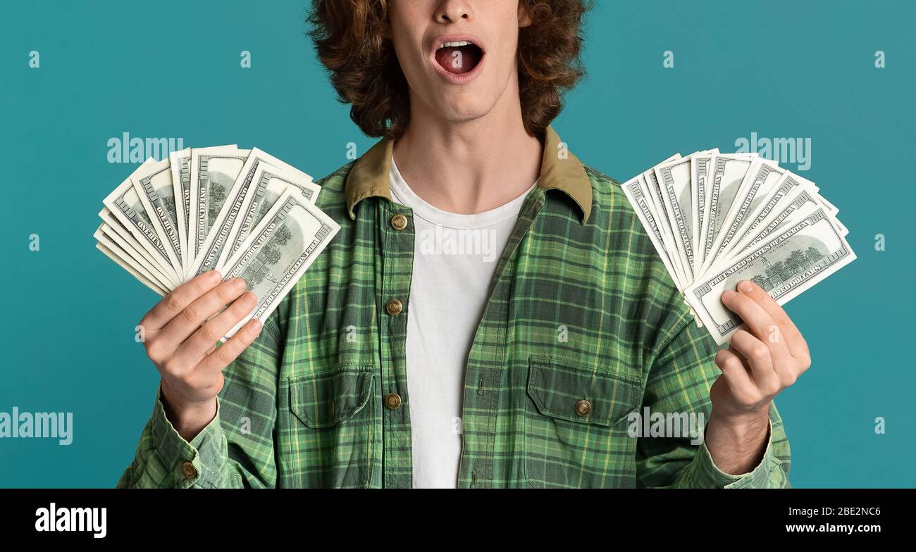 Winning lottery. Happy young guy with money shouting OMG on turquoise ...