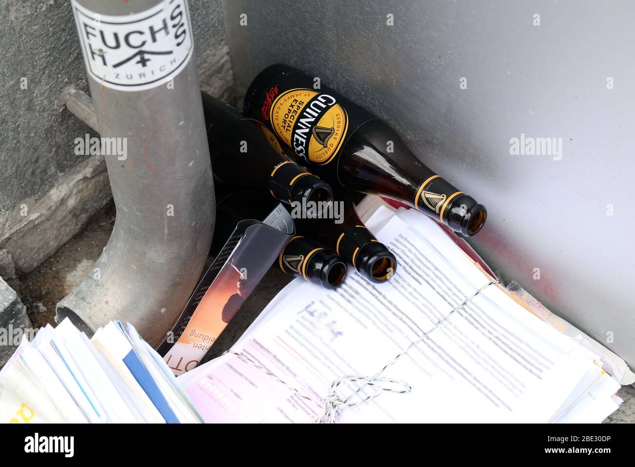 Guinness beer bottles and old papers left to a street corner near a ...