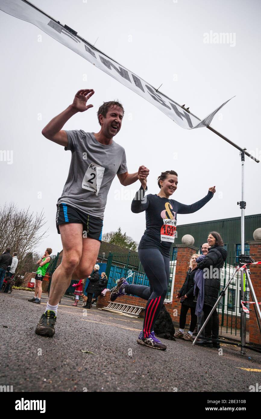 Man and woman hold hands as they cross the finish line in a Boxing Day ...