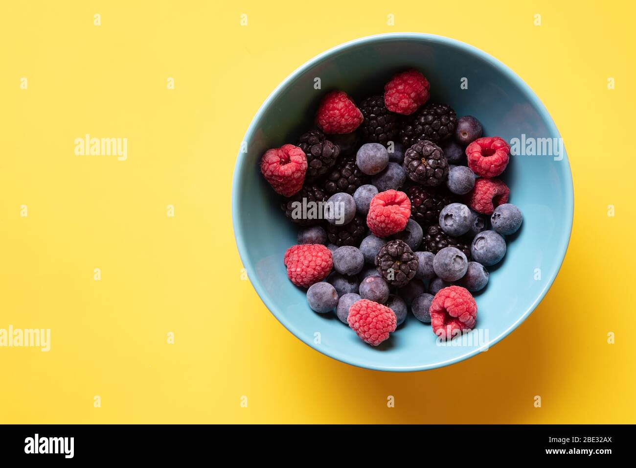 a beautiful light blue bowl of fruit with raspberries, blueberries and ...