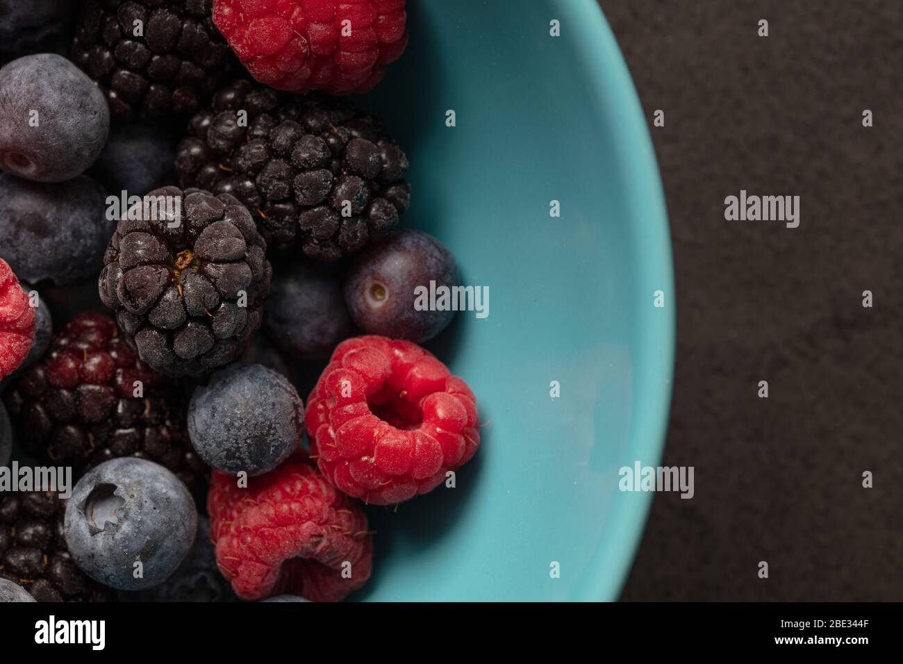 a beautiful light blue bowl of fruit with raspberries, blueberries and ...