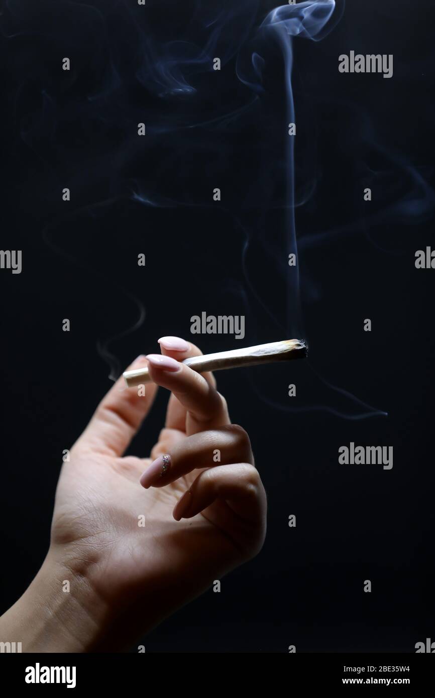 Woman hand holding cigarette. Smoking cannabis joint. Medical use ...