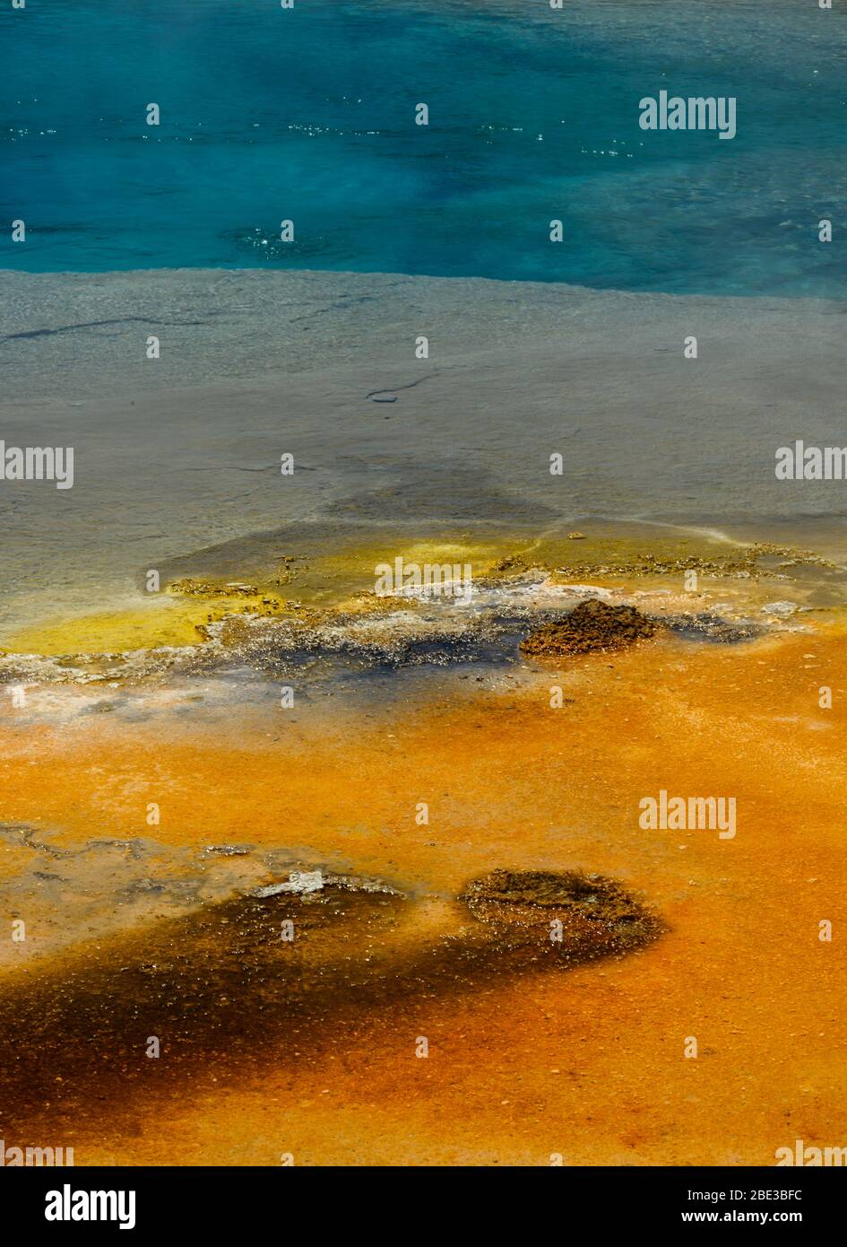 Golden Sulfur Residue in Hot Spring with blue waters behind Stock Photo ...