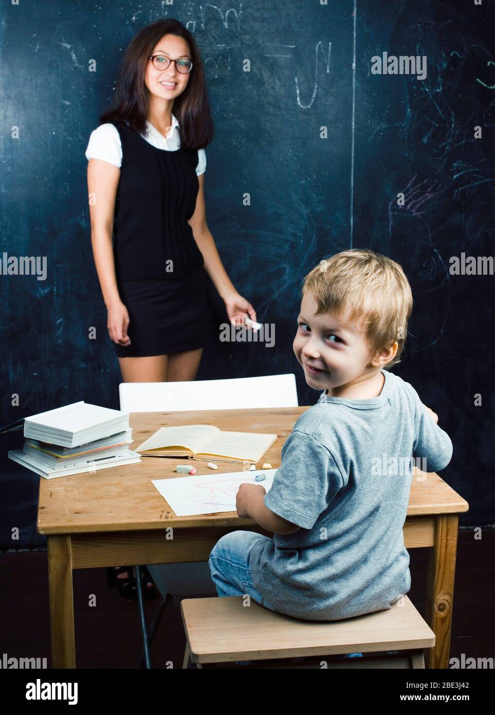 little cute boy in glasses with young real teacher, classroom studying ...