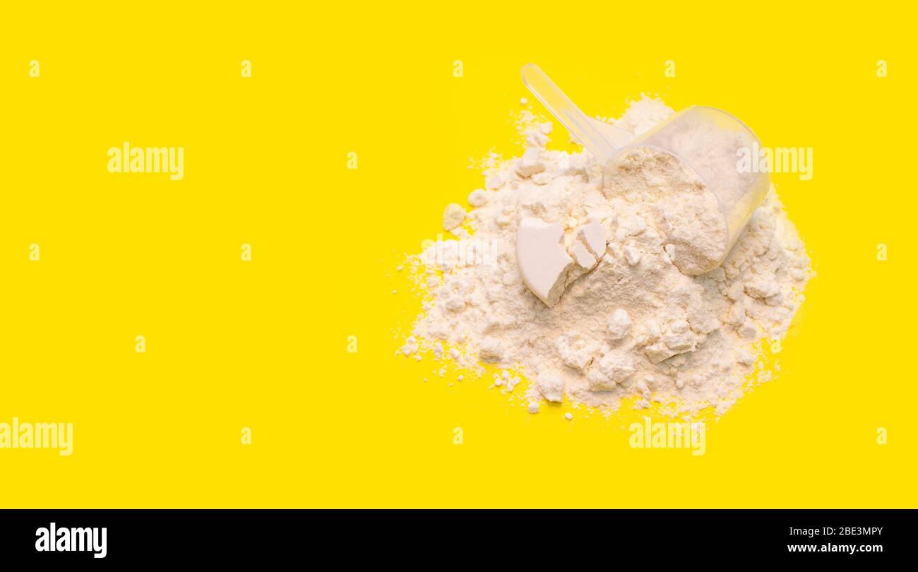 Heap of protein powder with plastic spoon on yellow background Stock ...