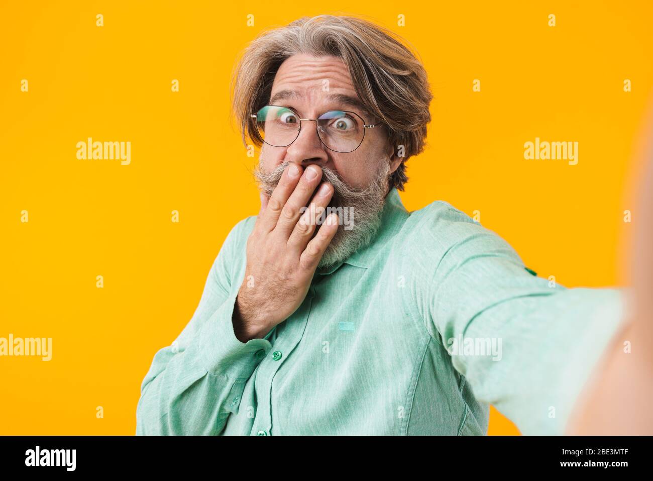 Picture of shocked grey-haired man posing isolated over yellow wall ...