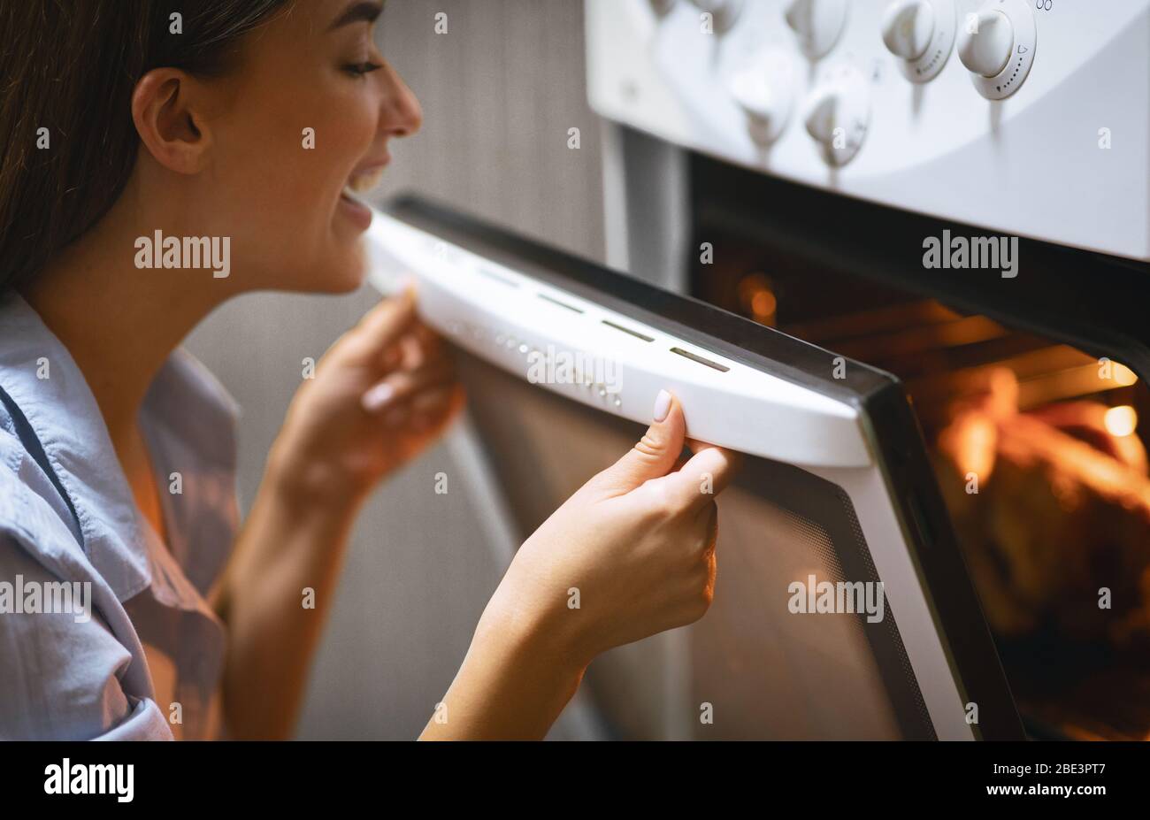 Excited woman opening oven with baking, cooking lunch Stock Photo - Alamy