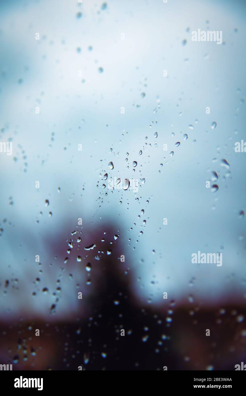 Selective focus of rain drops on a glass window surface with blurry ...