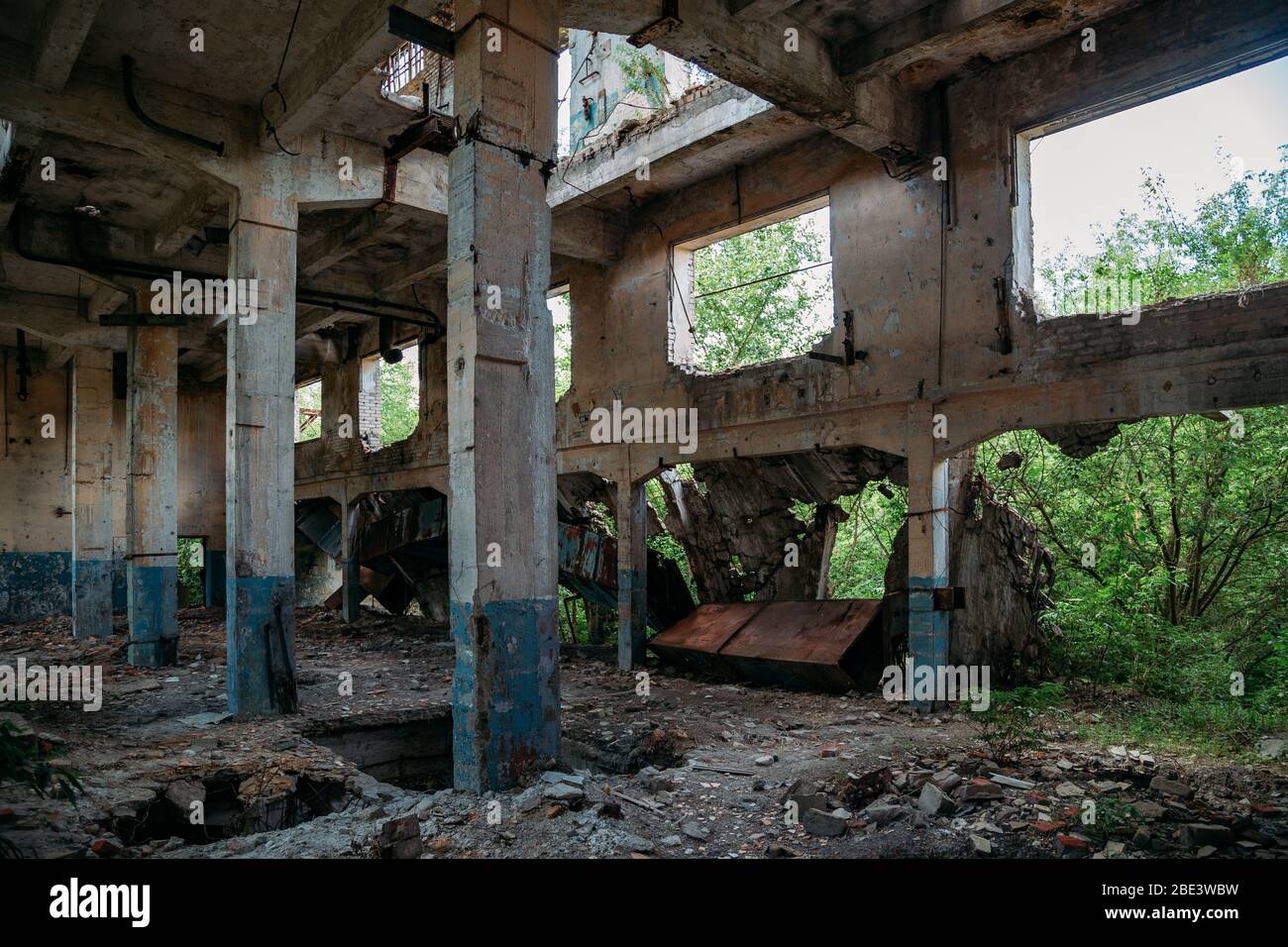 Old abandoned ruined industrial building overgrown by plants and trees ...