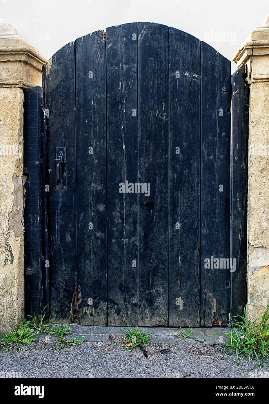 Black old wooden gate between yellow columns against white wall Stock ...