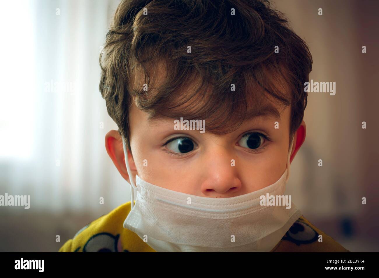 3 years old Turkish baby wearing surgical mask peering anxiously at one ...