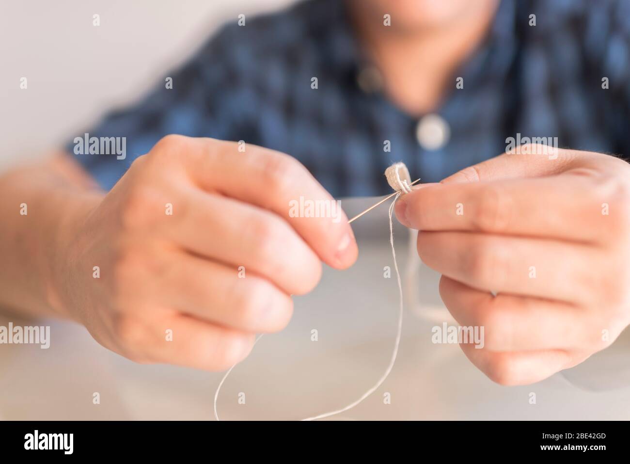 Hands sewing an elastic to an acetate plate. Process of making a ...
