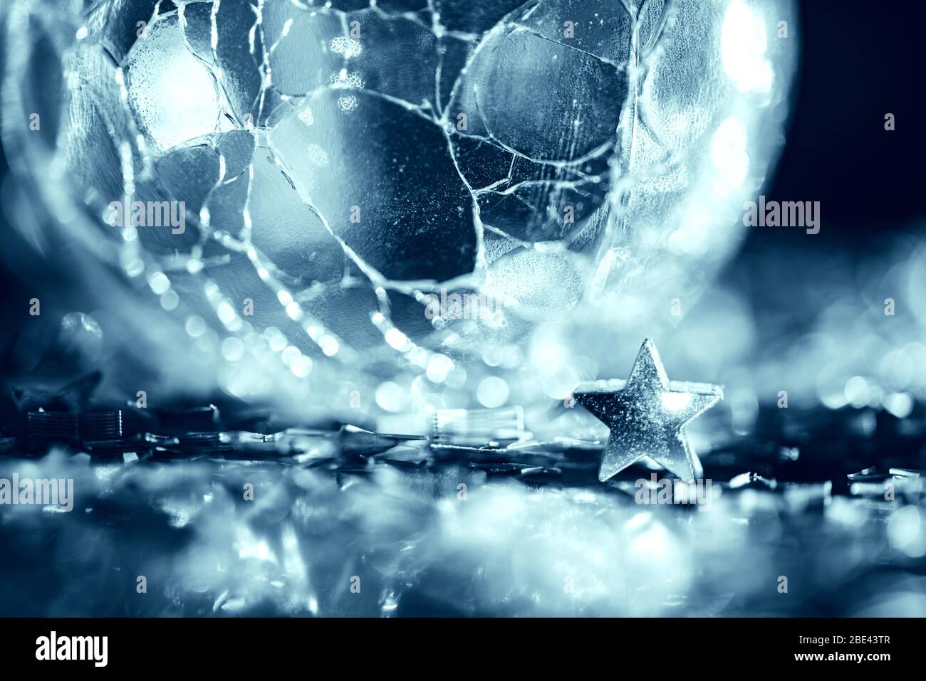 Macro photo of bright silver star and cracked glass sphere with light ...