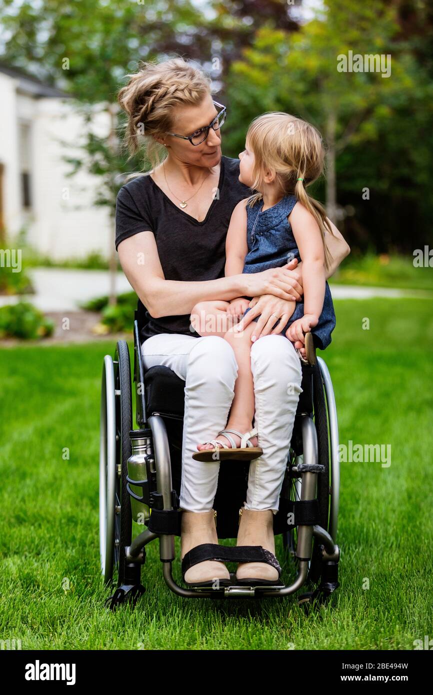 A paraplegic mom holding her little girl in her lap while sitting in ...