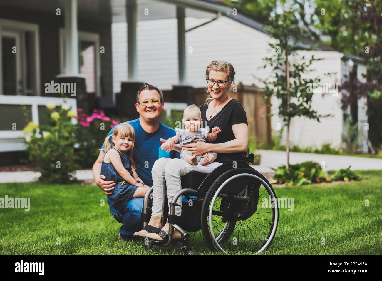 A young family posing for a family portrait outdoors in their front ...