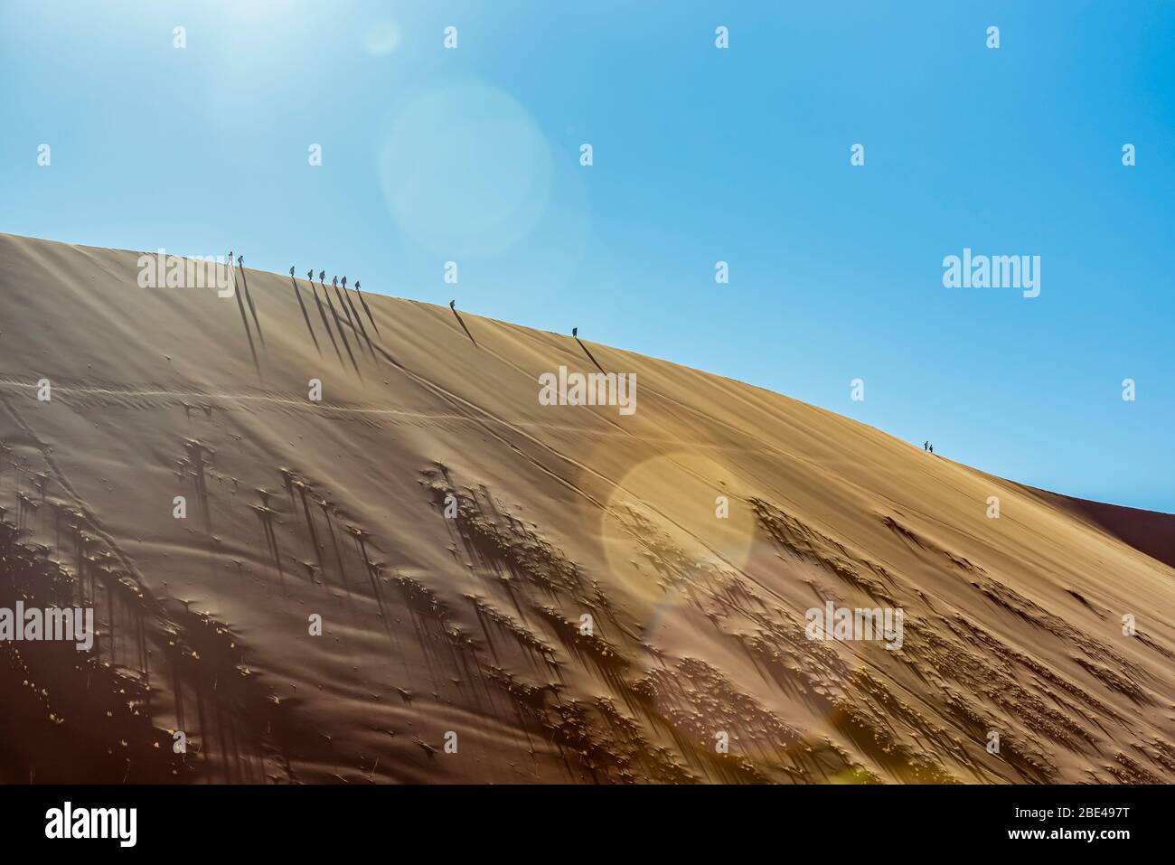 Tourists walking along a sand dune ridge at Deadvlei, a white clay pan ...
