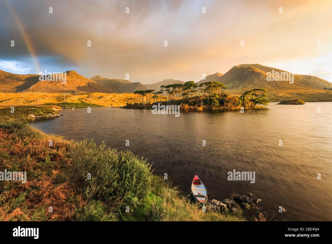 Canoe on the banks of a lake in Connemara with an island with trees at ...
