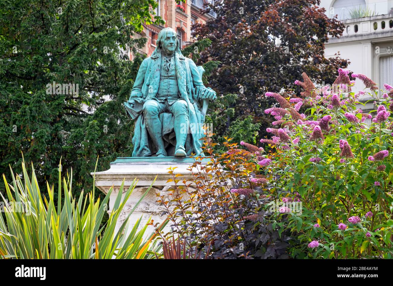 Benjamin Franklin statue in a garden with trees and blossoming plants ...