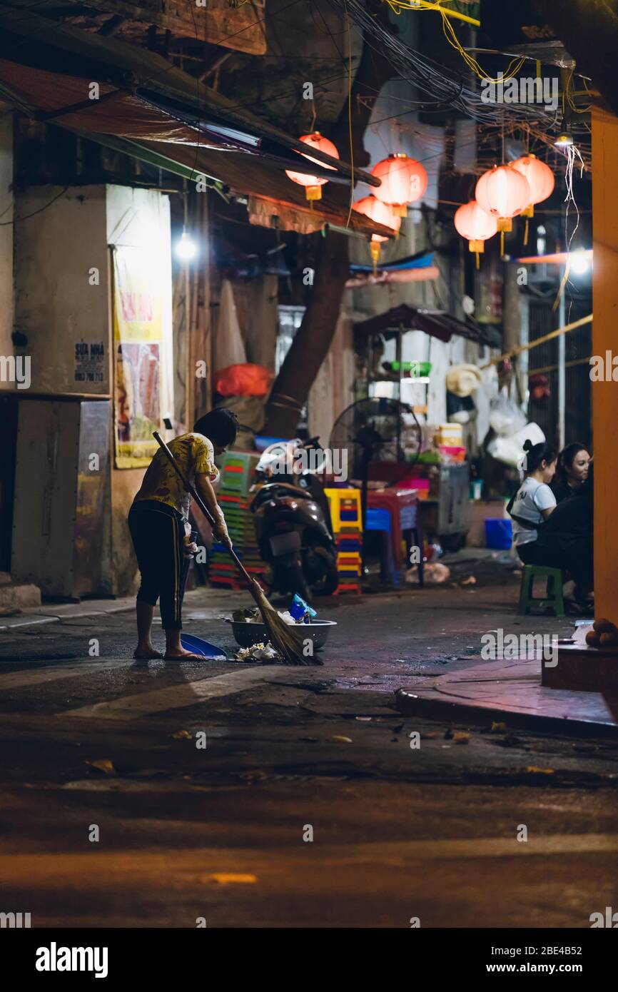 Woman sweeping up garbage in the street at night; Hanoi, Veitnam Stock ...
