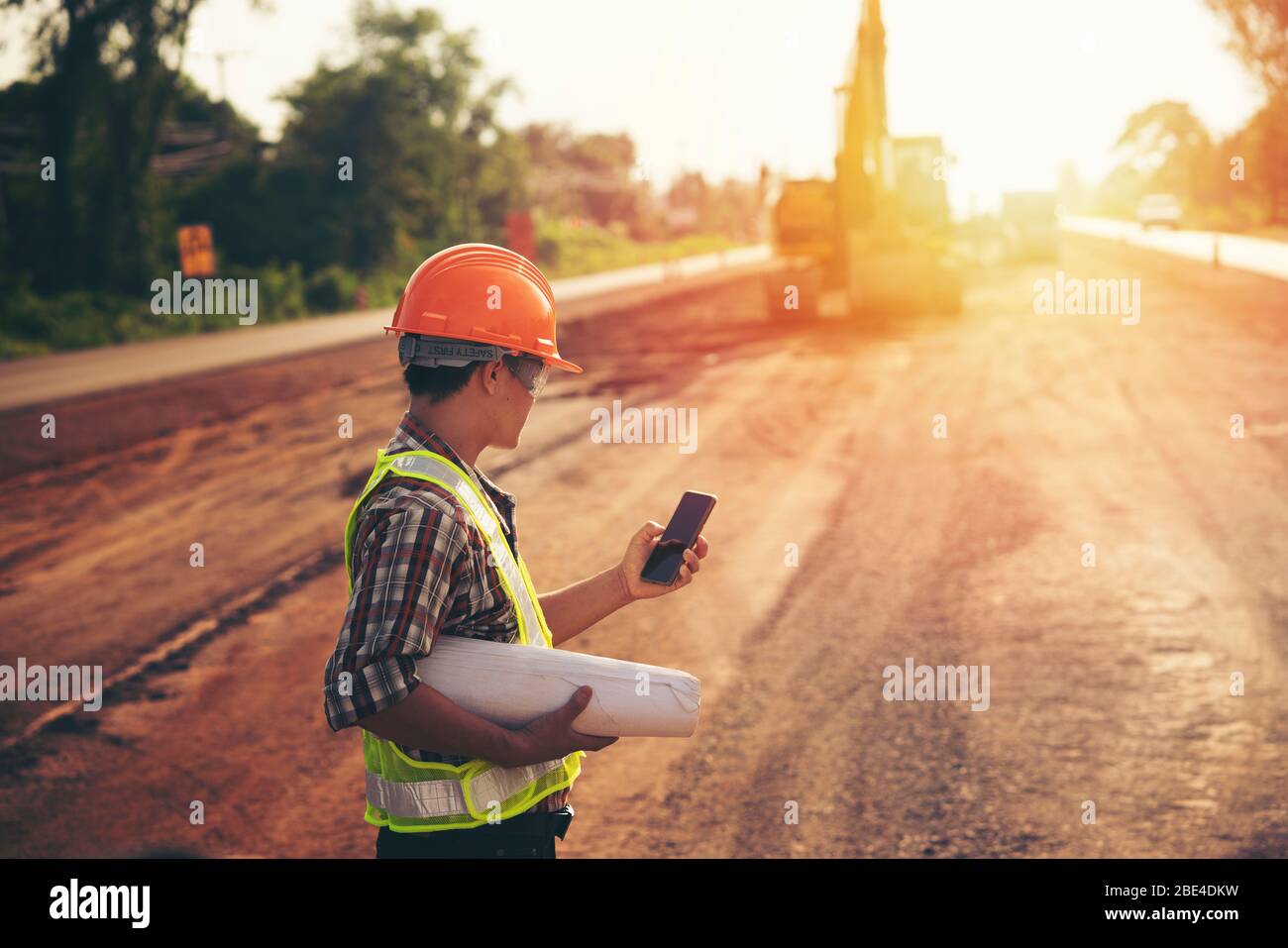Engineer wear a hard hellmet and holding blueprint on road construction ...