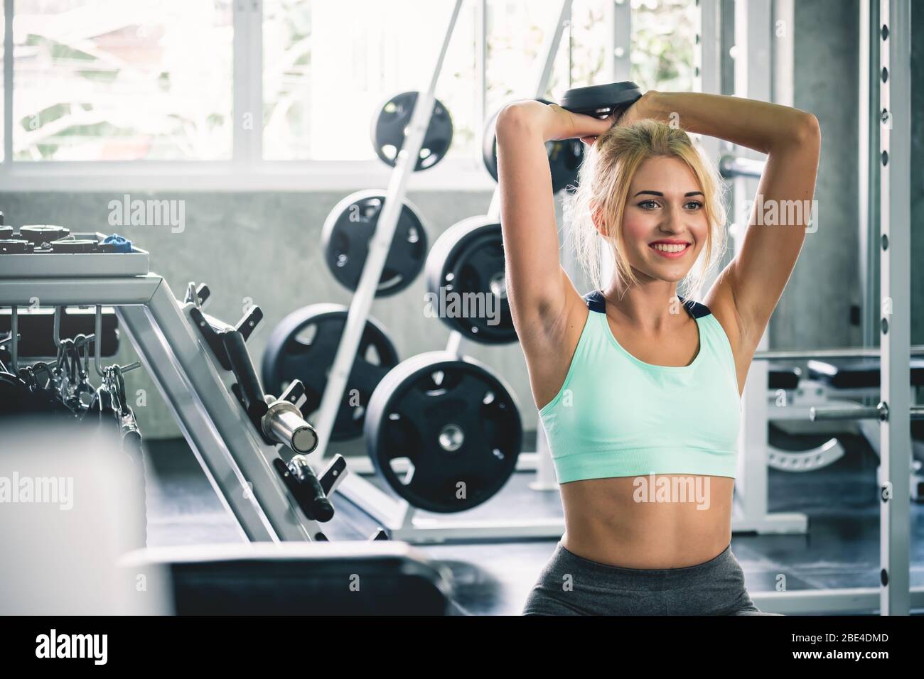Woman doing and lifting dumbbell for weight trainging at sport gym with ...