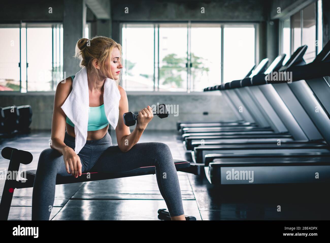 Woman workout by lifting dumbbell for weight training at sport gym ...
