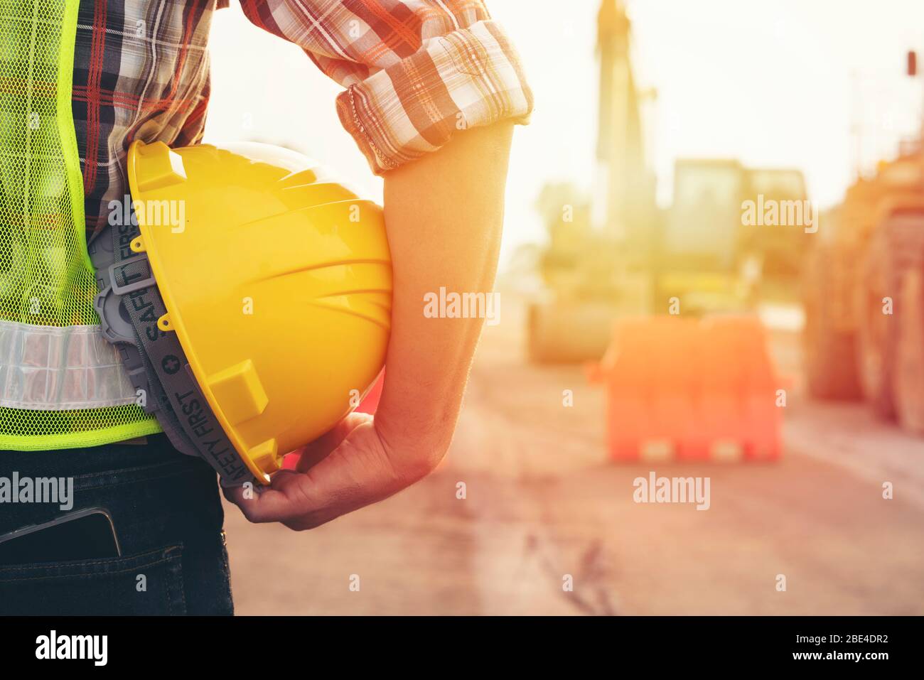 Engineer holding helmet at road construction site with machinery ...