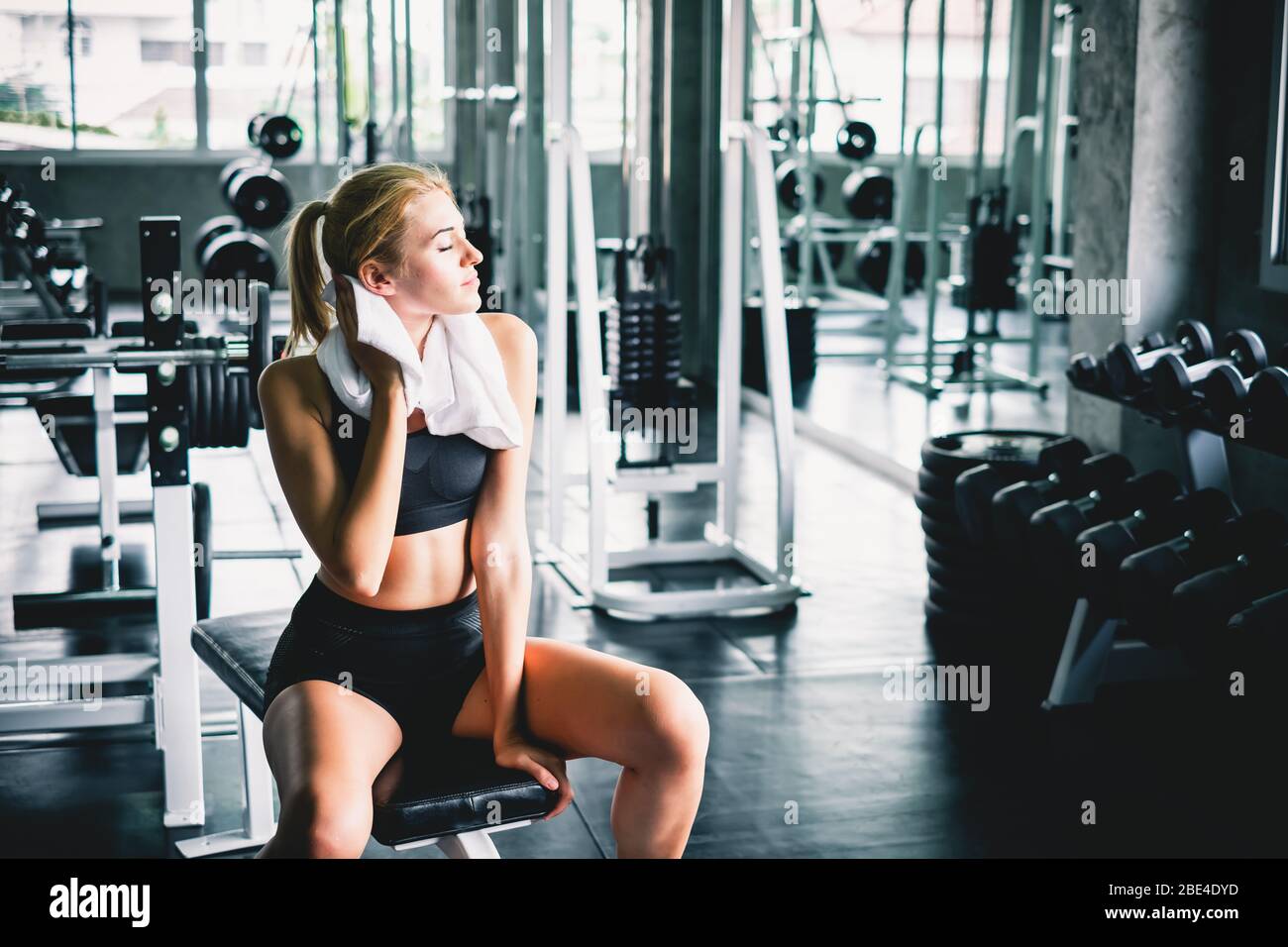 Woman relaxing after finishing workout and weight training at sport gym ...