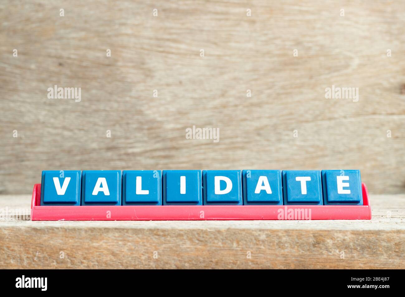 Tile letter on red rack in word validate on wood background Stock Photo ...