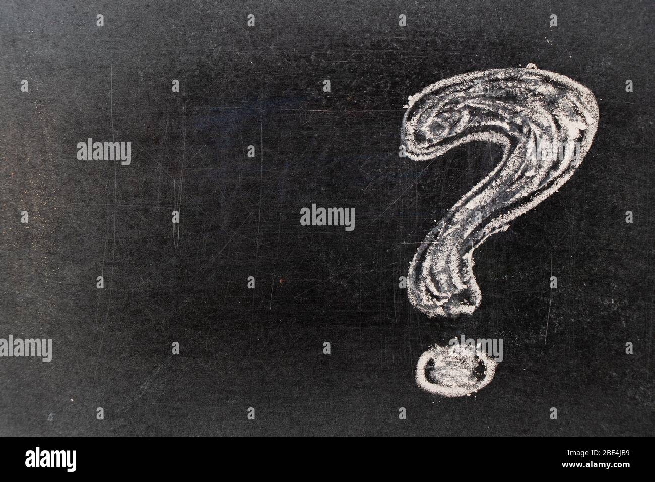 White color chalk hand drawing in question mark shape on blackboard ...