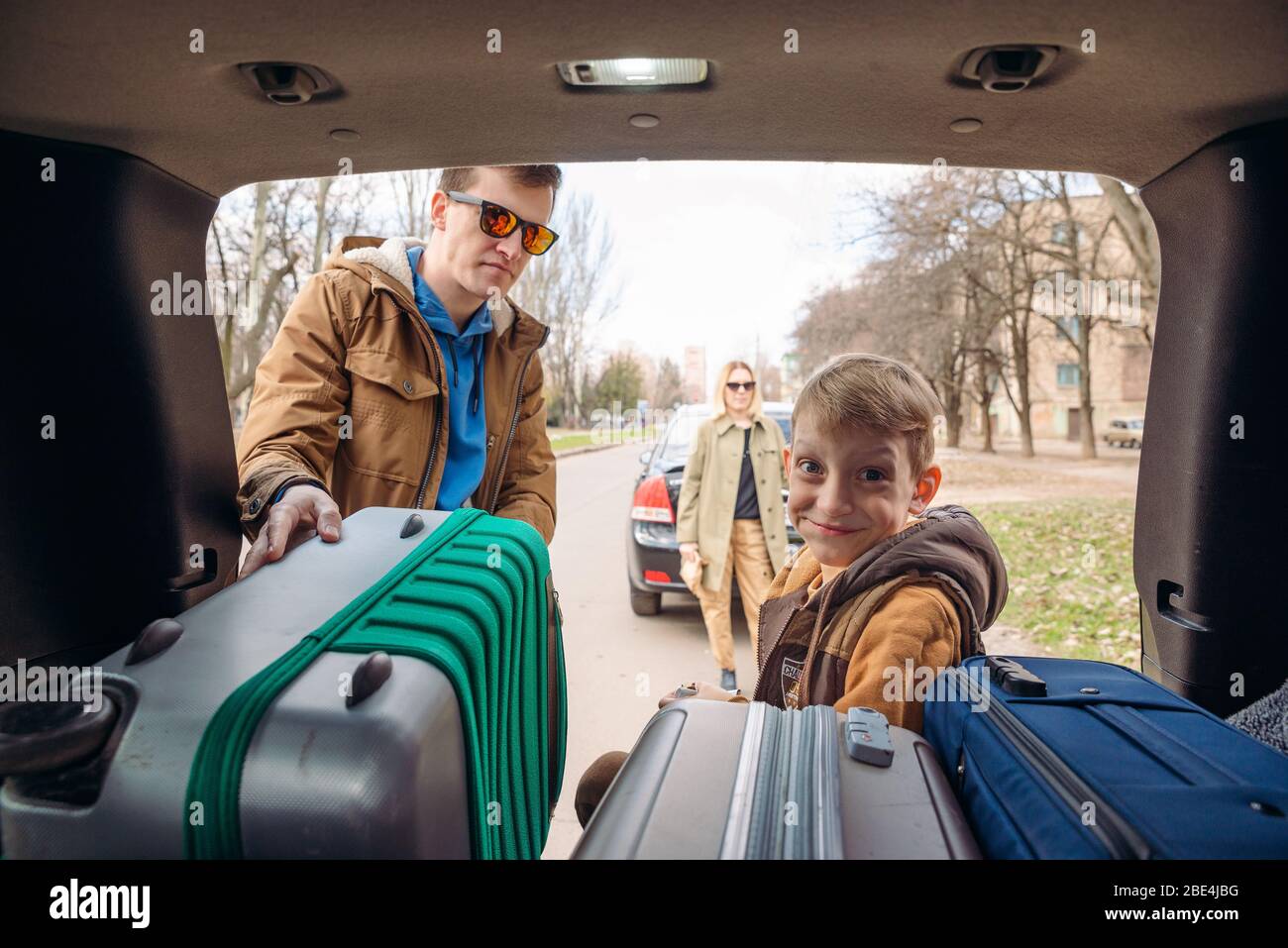 family with kid putting bag in car trunk Stock Photo - Alamy