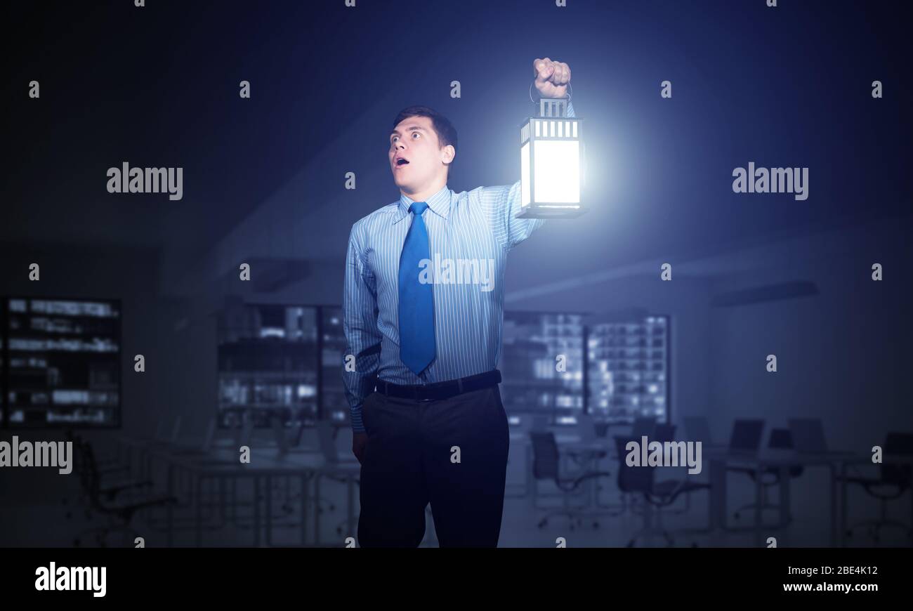 Scared businessman holding glowing lantern Stock Photo - Alamy