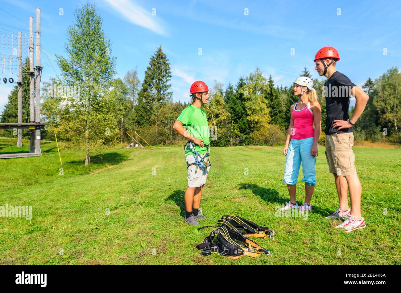 Preparing for climbing exercises in high ropes park with an instructor ...