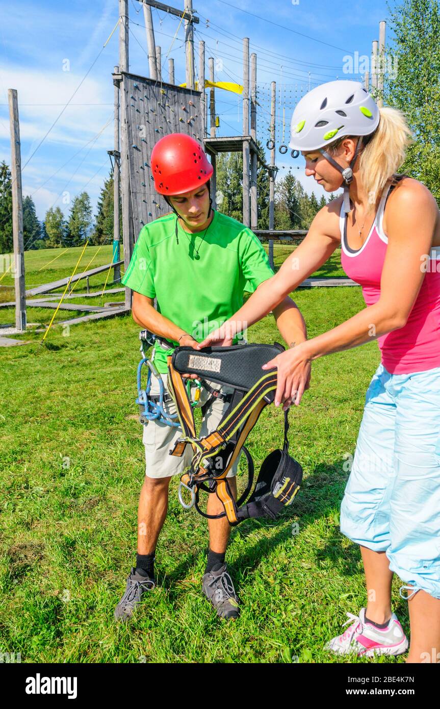 Preparing for climbing exercises in high ropes park with an instructor ...