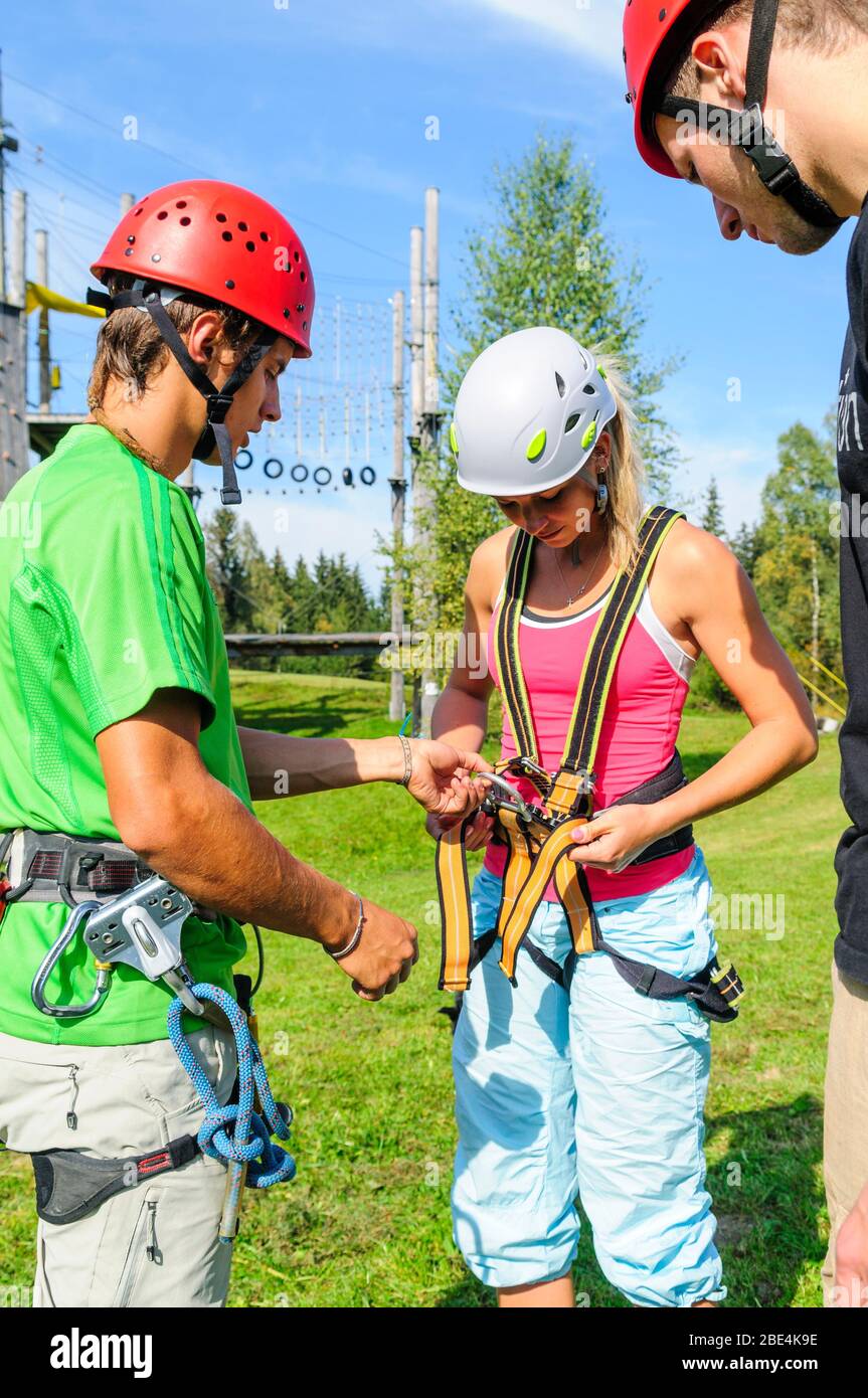 Preparing for climbing exercises in high ropes park with an instructor ...