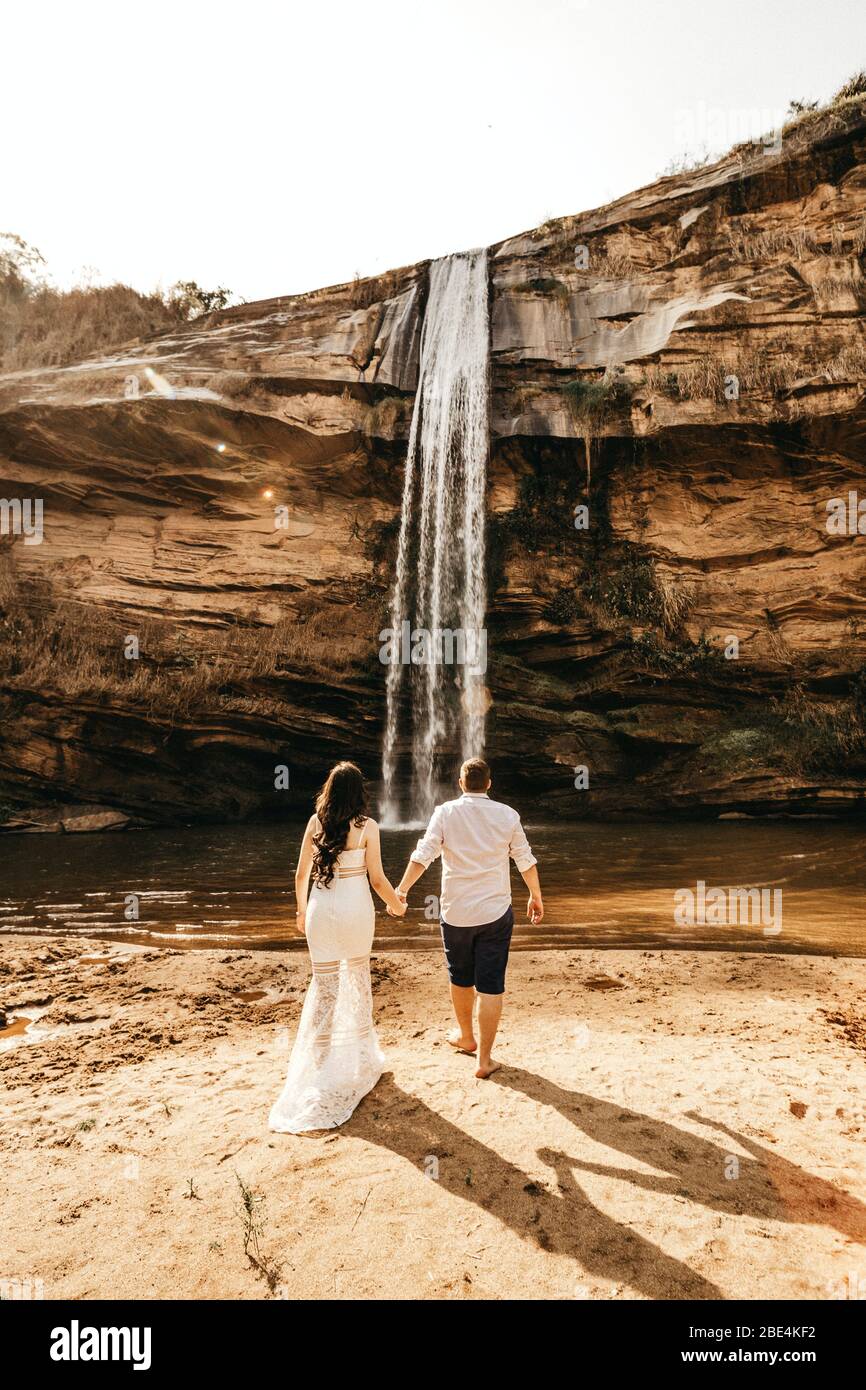 beautiful couple /woman and man walking through waterfalls while ...