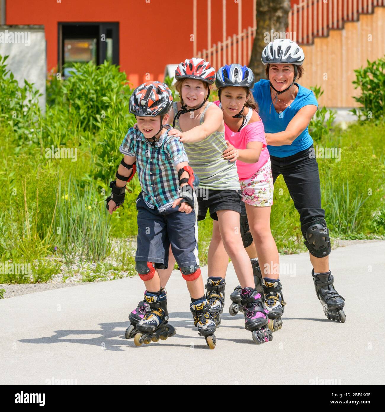Young family doing a tour on inline skates in urban park at a sunny ...