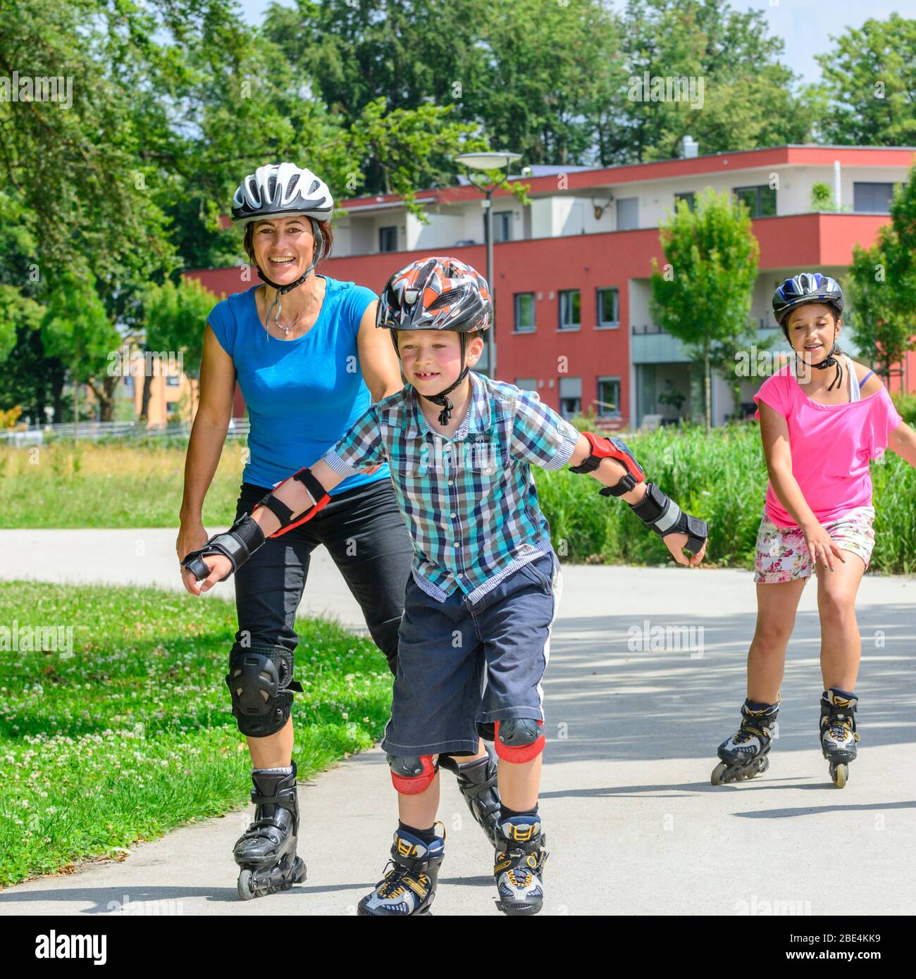 Young family doing a tour on inline skates in urban park at a sunny ...