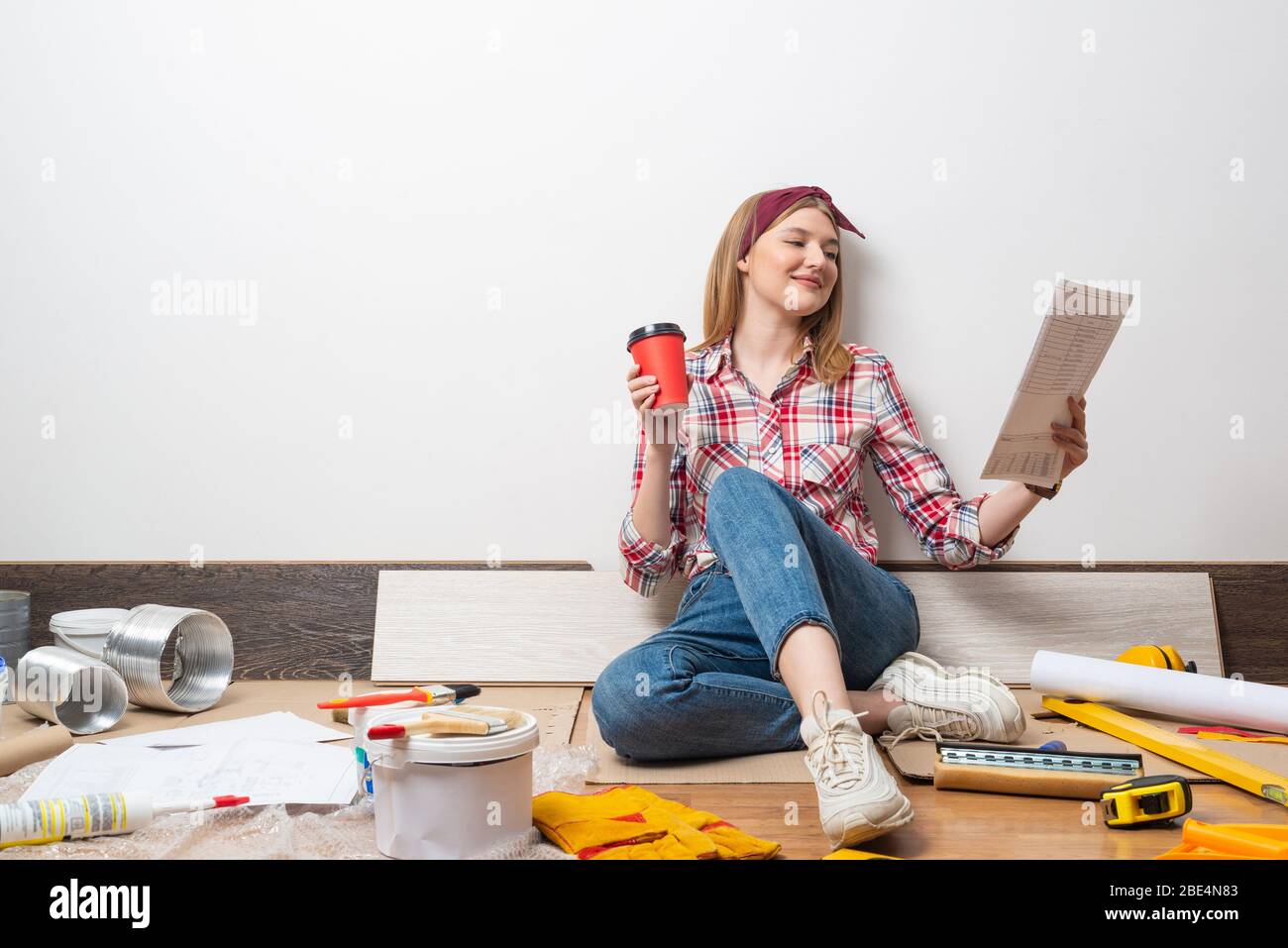 Smiling girl sitting on floor with blueprint Stock Photo - Alamy