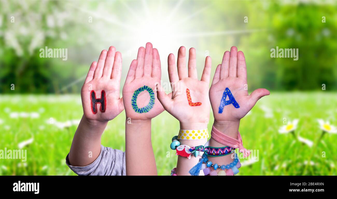 Kids Hands Holding Word Hola Means Hello, Grass Meadow Stock Photo - Alamy
