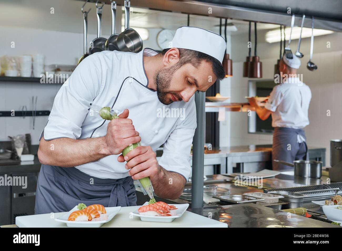 Chef making sushi at restaurant. He concentrates on adding wasabi paste ...