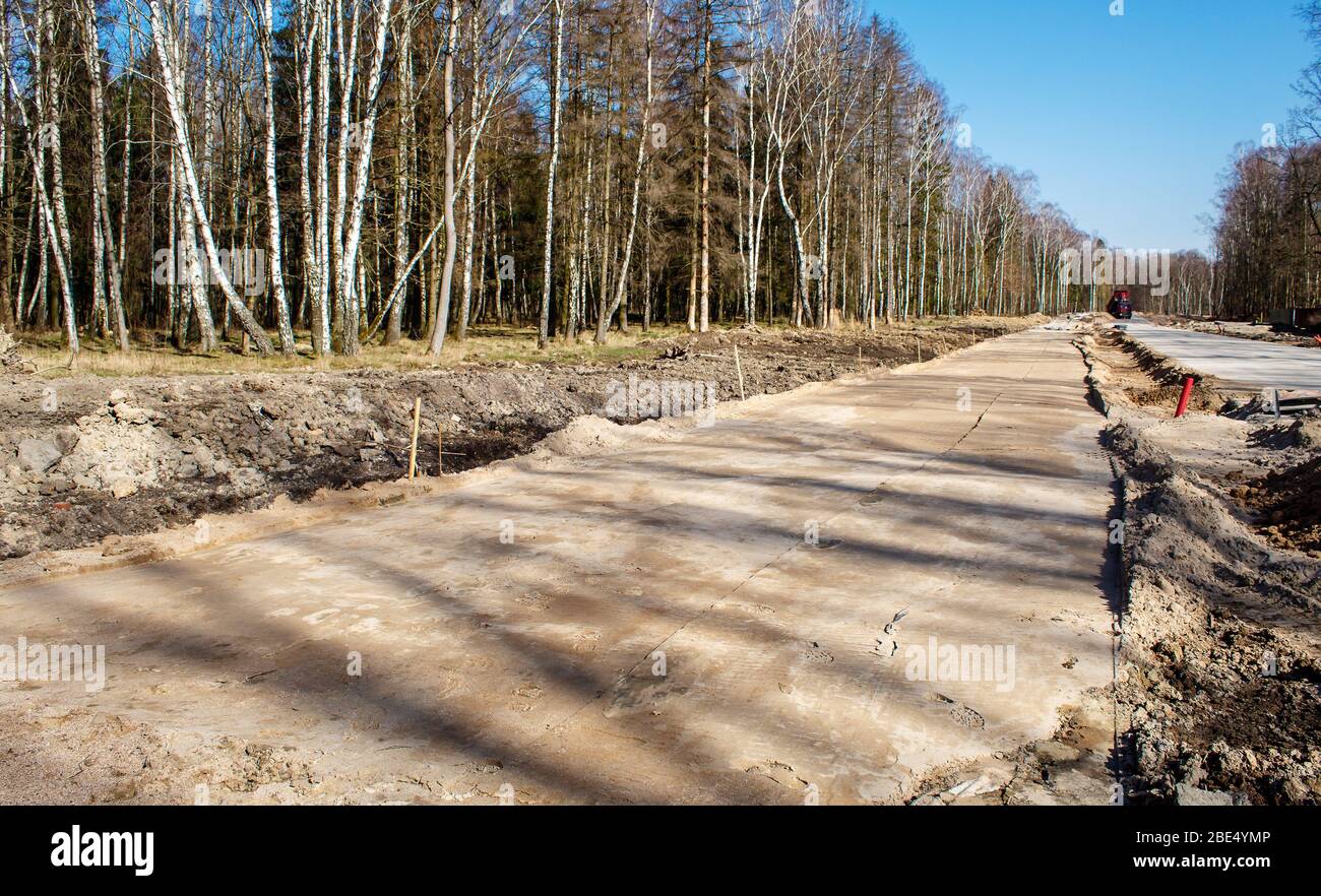 construction of a new modern road in the forest on sunny spring day ...