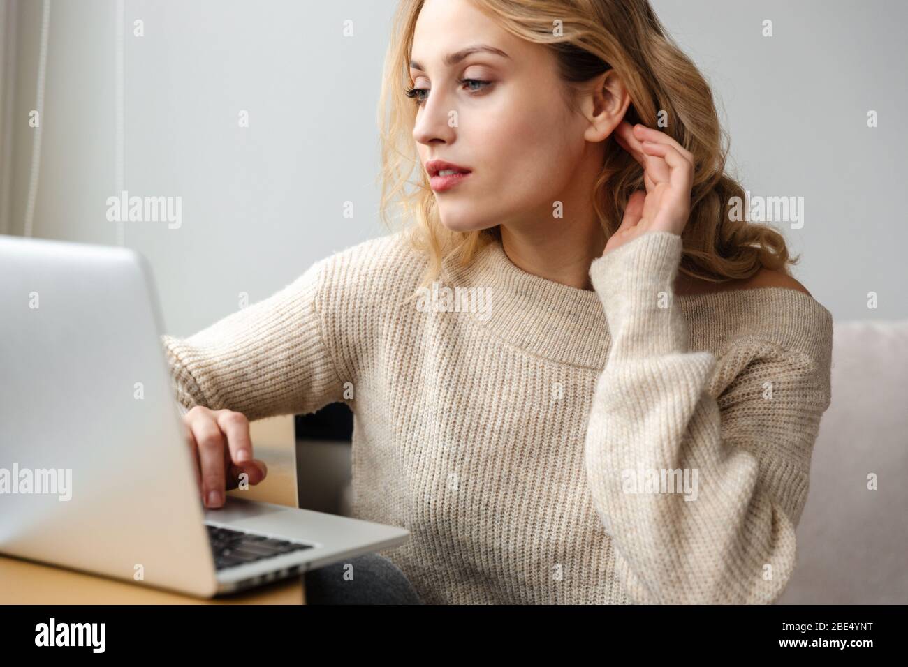 Image of a pretty serious young woman indoors at home using laptop ...