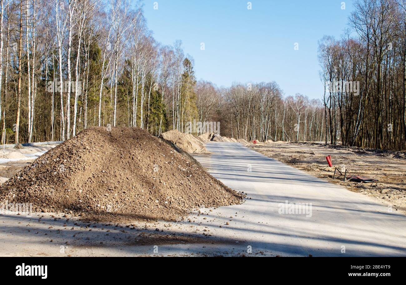 construction of a new modern road in the forest on sunny spring day ...
