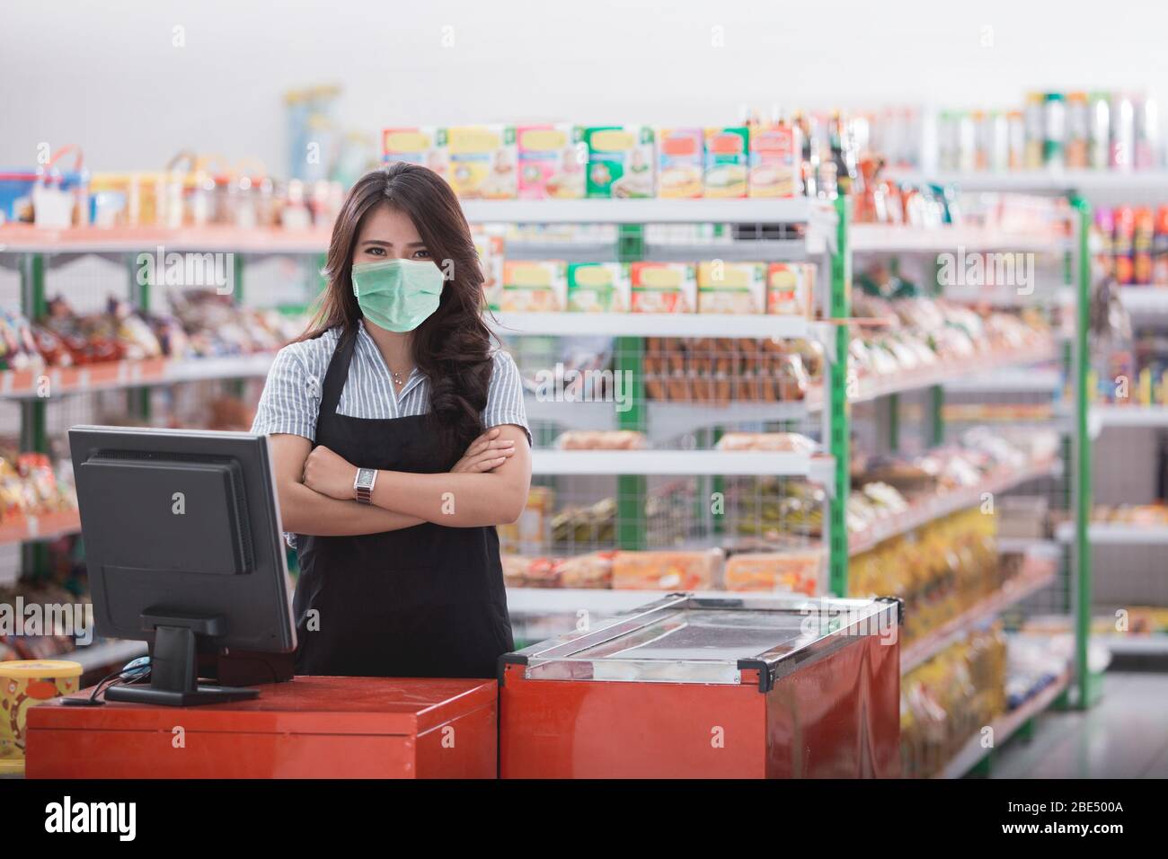 Portrait of smiling asian female cashier staff standing at cash counter ...
