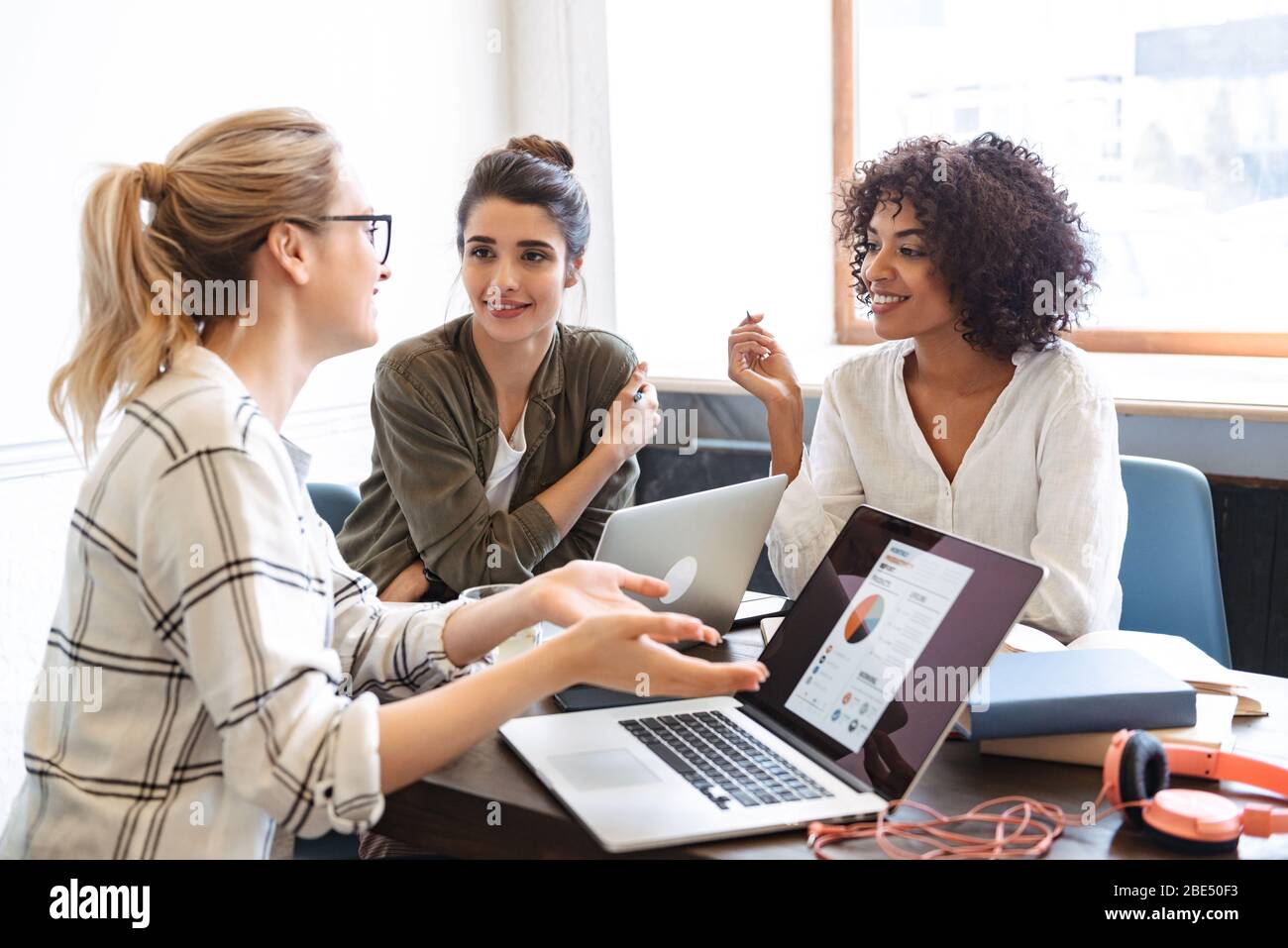 Group of multiethnic cheerful young women studying together at the ...