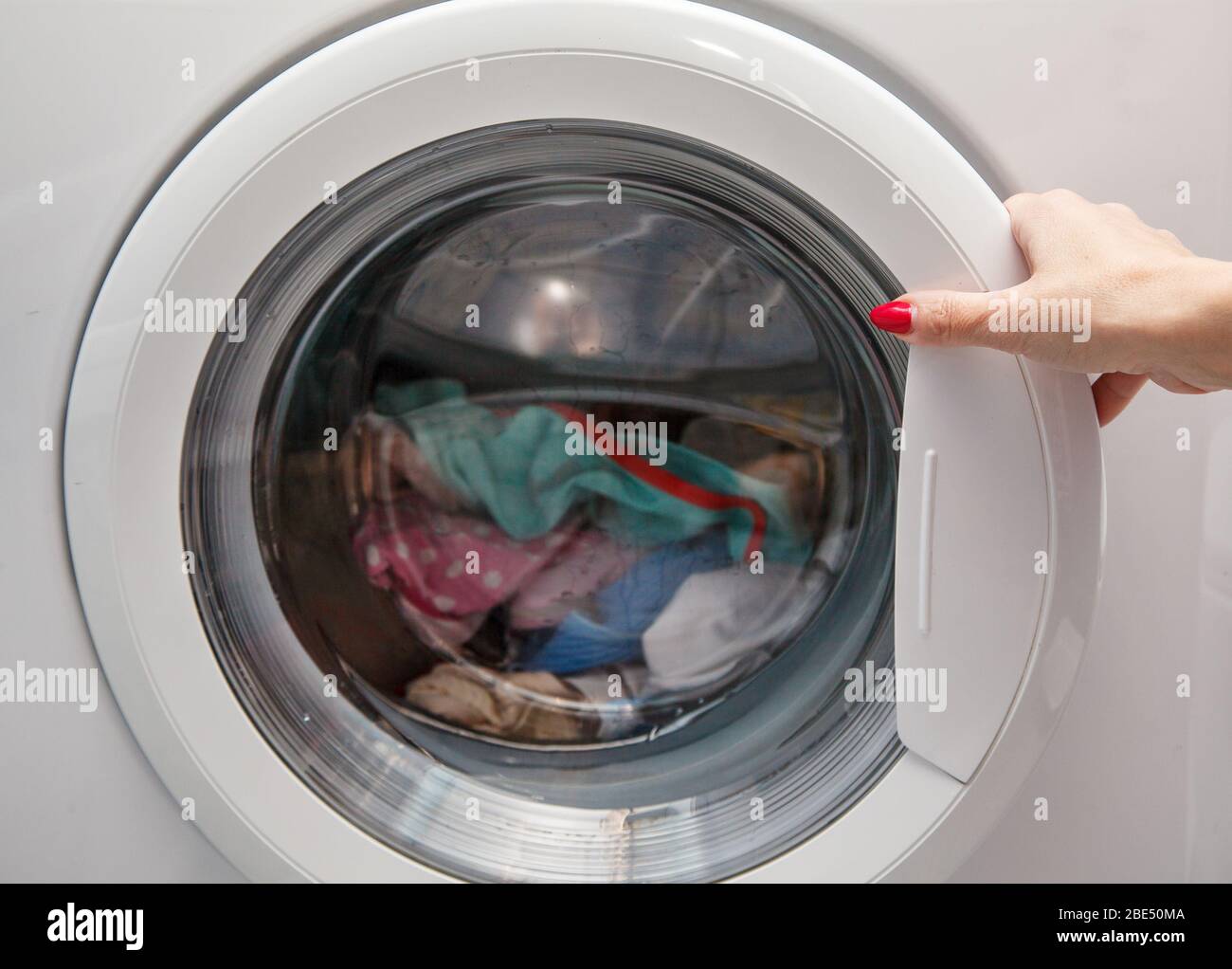 linen is loaded in the washing machine. female hand closeup Stock Photo ...